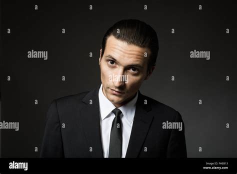 portrait of an attractive mysterious man in black suit and tie on dark ...