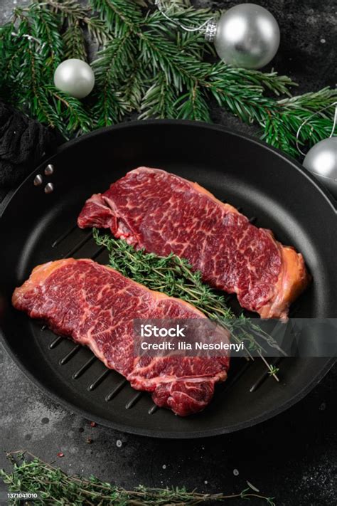 크리스마스 트리 장식이있는 생 뉴욕 쇠고기 스테이크 검은 어두운 돌 테이블 배경 검은색에 대한 스톡 사진 및 기타 이미지