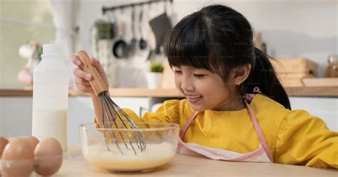 부엌에서 수제 빵집을 하는 아시아의 젊은 귀여운 소녀의 초상화 사랑스러운 어린 아이가 테이블에 앉아 행복한 느낌을 받고 홈에서