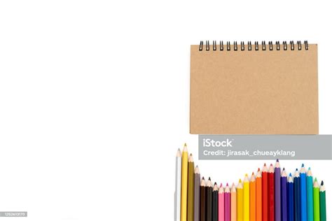 파도 패턴으로 배열 된 24 개의 색깔연필은 그림의 오른쪽 하단에 있으며 책은 그림의 오른쪽 상단 모서리에 있으며 모든 흰색 배경에 있습니다 0명에 대한 스톡 사진 및 기타