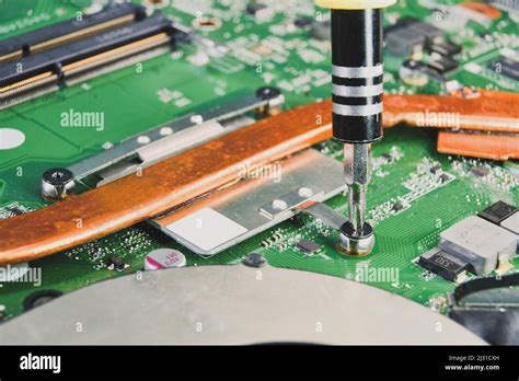 Mechanic Remove A Bolt From The CPU Heatsink Cooler Of The Computer Laptop With A Screwdriver
