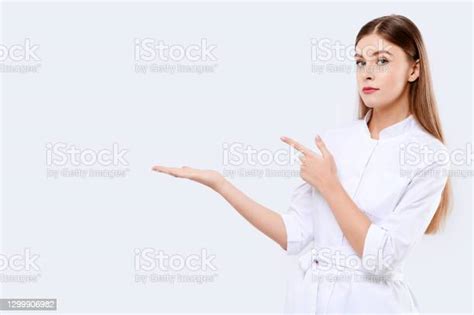 하얀 고립 된 배경에 유니폼을 입고 Felame 의사 뭔가를 보여주는 젊은 미소 간호사 병원 직원 간호사에 대한 스톡 사진 및 기타 이미지 Istock