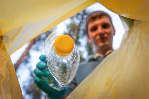 Premium Photo Garbage Collection In Nature Young Man Puts Plastic Trash In A Yellow Bag Inside