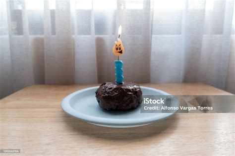 파란색 양초와 푸른 접시와 나무 테이블에 빛나는 불꽃 이모티콘이있는 작은 초콜릿 케이크 0명에 대한 스톡 사진 및 기타 이미지