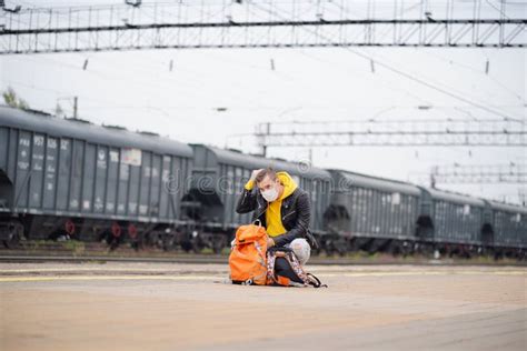 Young Man In Medical Mask Squats On Platform Waiting For Train Male