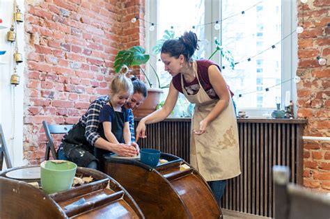 젊은 여성 강사 워크샵에서 도자기 바퀴를 사용하여 도자기를 수행하는 방법을 어머니와 그녀의 어린 소녀를 가르치고있다 25 29세에 대한 스톡 사진 및 기타 이미지 Istock