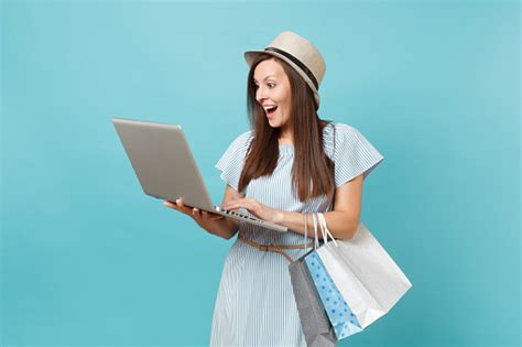 여름 드레스 온라인 쇼핑 후 구매와 패키지 가방을 들고 밀 짚 모자에에서 젊은 여자의 초상화 블루 파스텔 배경에 고립 된 노트북 Pc 컴퓨터를 사용 합니다 광고에 대 한