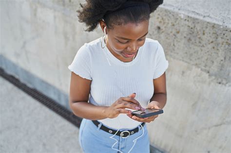 젊은 아프리카계 미국인 여성이 도시 환경에서 야외에서 음악을 듣기 위해 전화를 사용한다 20 29세에 대한 스톡 사진 및 기타 이미지 20 29세 30 39세