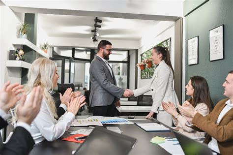 남성과 여성이 팀원들이 박수를 보내는 동안 Handshake로 비즈니스 파트너십을 확인합니다 계약서에 대한 스톡 사진 및 기타 이미지 Istock