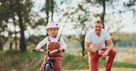 흰 셔츠를 입은 아버지가 딸에게 야외에서 자전거 타는 법을 가르치고 있다 사진 Unsplash의 의류 이미지