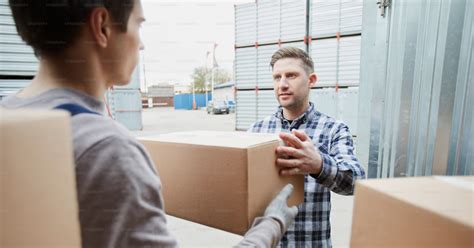 야외에서 화물 컨테이너에서 가져가는 동안 고객에게 판지 상자를 제공하는 젊은 발동기 사진 Unsplash의 판지 이미지