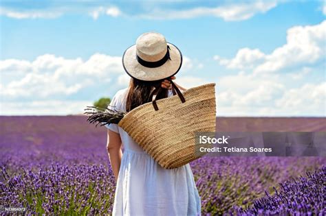 린넨 드레스와 밀짚 모자를 쓴 여성이 보라색 꽃 밭에 서서 밀짚 가방을 들고 멀리 바라 보는 모습 발렌솔의 여름 방학 프로방스 프랑스 후면에 대한 스톡 사진 및 기타 이미지