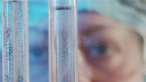 Slow Motion Woman In Goggles And A Cap Looks At The Diffusion Of Liquids In Test Tubes Work In