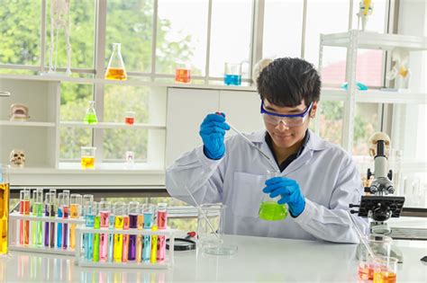 실험실에서 연구하기 위해 파이펫과 화학 유리 병을 들고 안경과 파란색 고무 장갑을 착용한 젊은 아시아 전문 의사 과학자의 초상화 25 29세에 대한 스톡 사진 및 기타