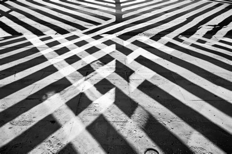 Intersecting Shadows Form Geometric Patterns Across A Concrete Surface Creating Dynamic Bold