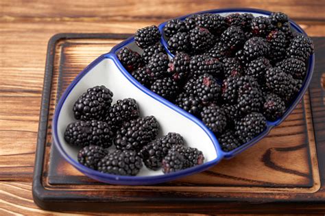 나무 배경에 도마에 파란색 테두리가있는 흰색 접시에 잘 익은 육즙이 많은 큰 유기농 블랙 베리 비건 음식 건강한 음식 텍스트 장소 상단 보기 개체 그룹에 대한 스톡 사진 및