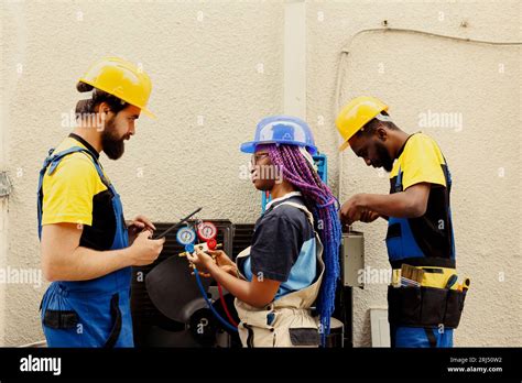 skilled technicians refilling freon and fixing leaks in external air conditioning unit