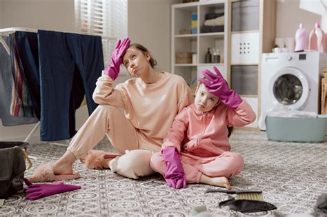 주부는 딸과 함께 바닥에 앉아 고무 장갑으로 턱 밑을지지하고 퇴근 후 여성을 쉬게합니다 집안일 후 피곤한 지친 소녀들 크리스마스 준비 어머니에 대한 스톡 사진 및 기타