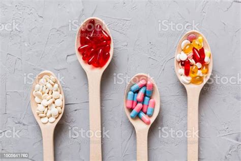 색깔이있는 배경에 숟가락에 비타민 캡슐 알약은 건강한 식사로 사용되었습니다 숟가락에 빨간 소프트 젤 비타민 보충 캡슐 0명에