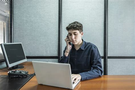 사무실에서 전화 통화를 하는 동안 노트북으로 작업하는 청년 사진 Unsplash의 십대 소년 이미지