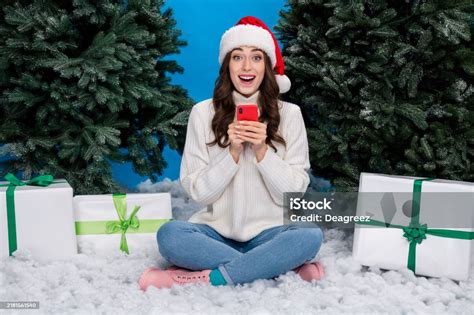 감동 흥분 아가씨 산타 클로스 도우미 모자를 착용 앉아있는 눈 선택 현대 가제트 크리스마스 선물 절연 블루 컬러 배경 사진 20 24세에 대한 스톡 사진 및 기타 이미지