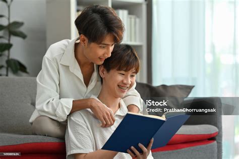 행복한 게이 커플은 집에서 소파에 앉아 책을 읽고 주말에 함께 시간을 보낸다 Lgbtq 사람들의 라이프 스타일과 사랑 감정 20 24세에 대한 스톡 사진 및 기타 이미지