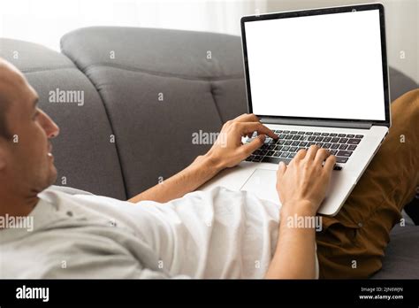 Young Male Tech User Relaxing On Sofa Holding Laptop Computer Mock Up