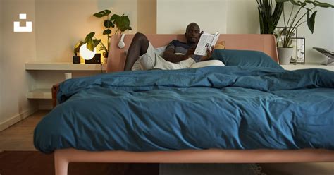 검은 티셔츠와 회색 바지를 입은 남자가 파란 침대에 누워 있다 사진 Unsplash의 무료 침대 이미지