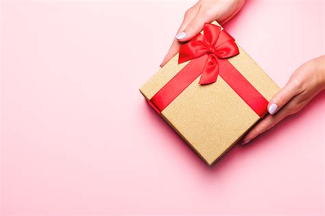 파스텔 핑크 색 배경에 빨간색과 금색 선물 상자를 들고 있는 여성 하트 모양의 색종이 카피스페이스 발렌타인 데이 인사말 카드 또는 트렌디 한 색상의 어머니의 날 휴일 카드