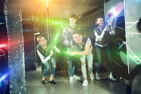 人们穿着背心，拿着激光枪在玩激光游戏