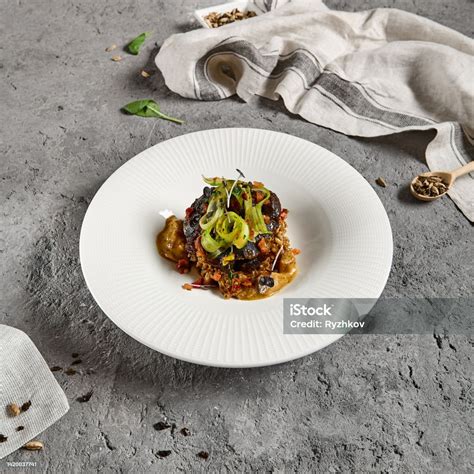 진주 보리와 샐러리를 크림 버섯 소스로 찐 쇠고기 뺨 회색 돌 배경에 버섯 리조또가있는 송아지 고기 뺨 메인 코스 개념 레스토랑을위한 음식 메뉴 고기에 대한 스톡 사진 및