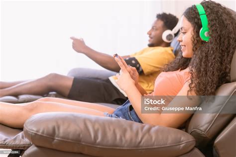 비디오 게임 콘솔로 재미있게 지내는 소년 스마트 폰을 보는 소녀 젊은 밀레니엄 세대 사람들은 집에서 휴일에 놀고 웃고 있습니다 기술 개념 소녀에게 집중하십시오 경기 스포츠에