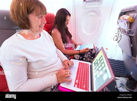 Airplane Passengers In Flight Using Laptop Computer And Ipad Tablet Computers In The Plane Cabin