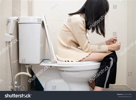 Young Asian Woman Sitting On Toilet Bowl Suffering Constipation