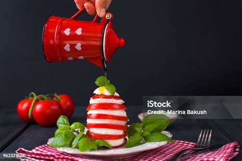 전통적인 이탈리아 Caprese 샐러드어두운 배경에 토마토 모 짜 렐 라 치즈와 바 질 슬라이스 닫습니다 여성 손 기름 부 어 건강한 생활방식에 대한 스톡 사진 및 기타