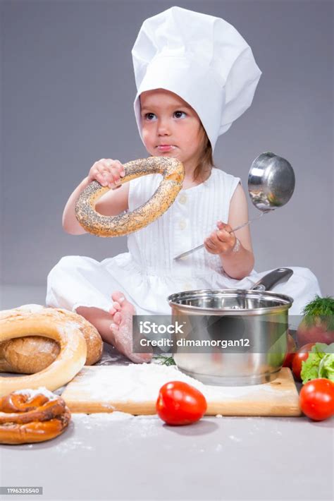 어린이 아이디어와 개념 스튜디오 환경에서 도너트 롤 국자 및 냄비와 함께 포즈를 취하는 요리 유니폼의 백인 소녀회색 배경에 대해 포즈 수직 이미지 컴포지션 2 3 살에 대한