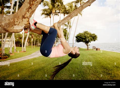 Side View Of Woman Hanging On Tree Branch At Grassy Field Stock Photo Alamy