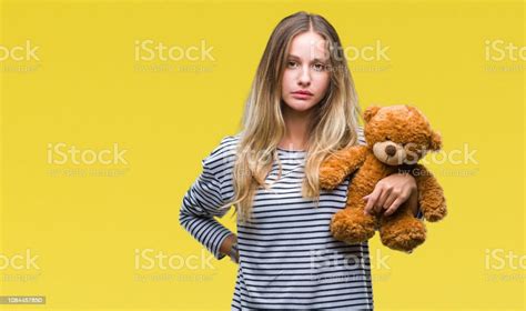 스마트 얼굴 심각한 생각에 자신감이 식으로 고립 된 배경 위에 테 디 베어 봉 제를 들고 젊은 아름 다운 금발 여자 감정에 대한 스톡 사진 및 기타 이미지 Istock