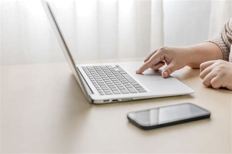 노트북과 스마트폰이 있는 창가 책상에서 재택근무를 하는 여성 Brand Name Smart Phone에 대한 스톡 사진 및 기타 이미지 Brand Name Smart