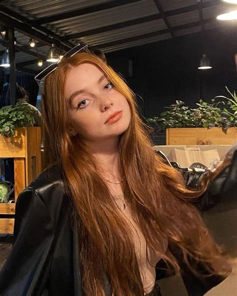A Woman With Long Red Hair Sitting At A Table