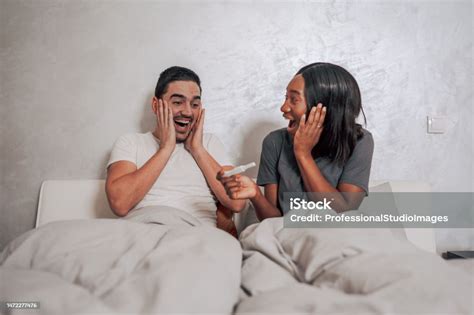 국경없는 사랑 다민족 커플은 침실에서 긍정적 인 임신 테스트를 축하합니다 20 24세에 대한 스톡 사진 및 기타 이미지 20