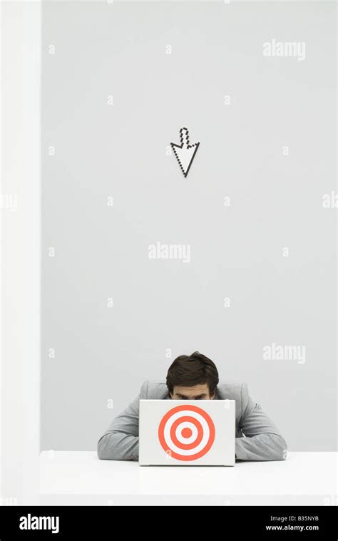 Computer Cursor Pointing At Businessman Hiding Behind Target Stock