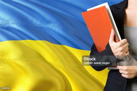 우크라이나어 언어 개념을 학습 백그라운드에서 우크라이나 국기와 함께 서 있는 젊은 여자 책을 들고 교사 오렌지 빈 책 표지 교사 교육 관련 직업에 대한 스톡 사진 및 기타