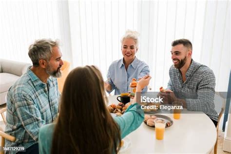 실내에서 함께 식사하는 행복한 가족 아침 식사 중에 식탁에 앉아 웃는 세대 가족 거실에서 함께 식사를 즐기는 행복한 쾌활한 가족 4 명에 대한 스톡 사진 및 기타 이미지