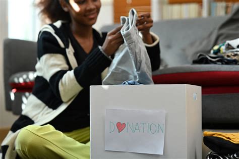 웃고 있는 젊은 여성이 거실의 기부 상자에 옷을 포장하는 자른 이미지 자선 기부 및 재사용 재활용 개념 Charitable Foundation에 대한 스톡 사진 및 기타