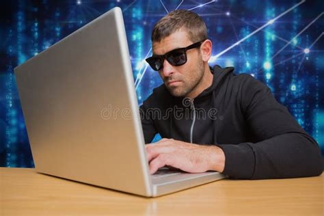 Cyber Criminal Wearing Black Glasses Is Hacking From A Laptop On A Desk Against Matrix Code Rain