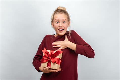 깜짝 얼굴 표정으로 포즈를 취하는 선물로 매력적인 금발 소녀 스튜디오 샷 화이트 배경 고립 10 11세에 대한 스톡 사진 및