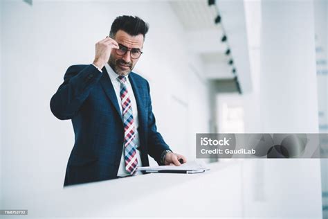 금융 회사의 사무실 내부에 문서와 함께 서 정장 옷을 입고 중년 사업가의 절반 길이 초상화 성공적인 성숙한 기업가 에 공식적인 착용 보고 에 카메라 50 54세에 대한 스톡