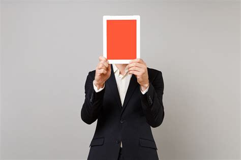 젊은 비즈니스 남자가 클래식 정장 숨기기 및 빈 빈 화면 회색 배경에 고립 된 Tablet Pc 컴퓨터와 얼굴을 덮고 있다 성과 경력 부 비즈니스 개념입니다 복사 공간을