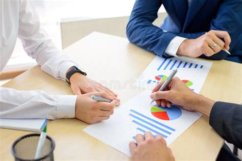 Business People Analyzing Financial Results On Graphs Around The Table In Modern Office Team